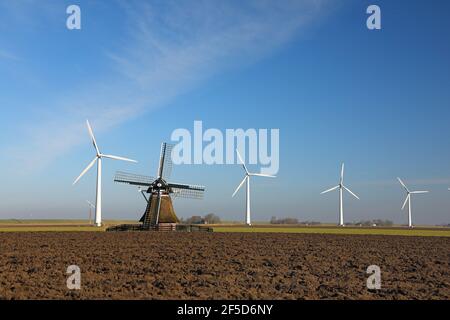windmill and wind wheels on the dyke in mist, Netherlands, Frisia ...