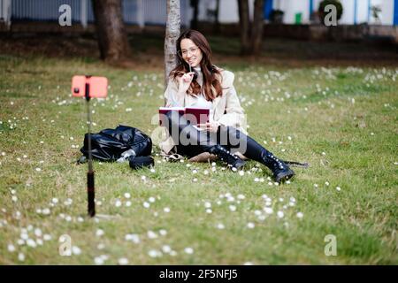 smiling female student learning remotely outdoors in park Stock Photo ...