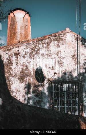 A vertical shot of a satellite dish on a cloudy day in black and white ...