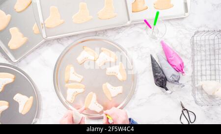 Flat lay. Decorating ice skate shaped sugar cookies with black color ...