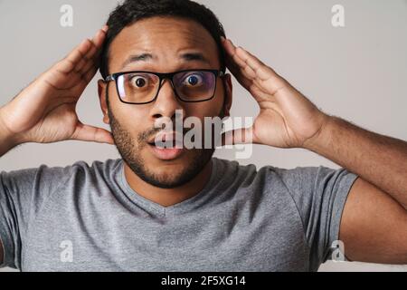 Asian young unshaven scared man grabbing his head isolated over yellow ...