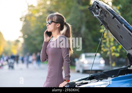 Unhappy young woman waiting angrily while her friend is talking happily on sellphone with ...