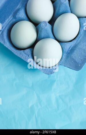 Eggs in carton on blue background Stock Photo - Alamy