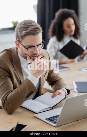 Thoughtful young woman with notebook near open fridge in kitchen Stock ...