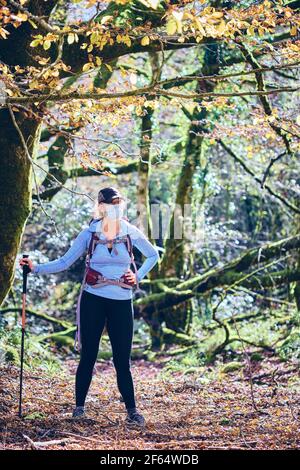A Caucasian female with a backpack and face mask walking on the ...