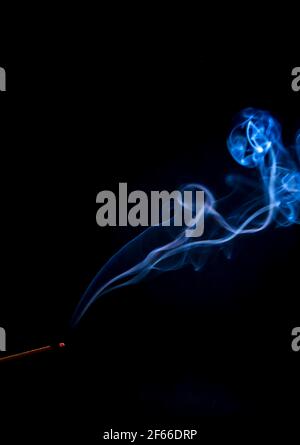 Incense stick lit and fuming on black background Stock Photo - Alamy