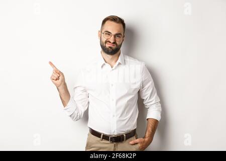 Skeptical male entrepreneur grimacing, pointing finger left with ...