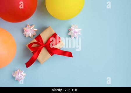 Gift with orange bow and colorful balloons on the yellow background ...