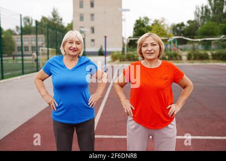 two adult women 58 and 64 years old doing exercises outdoors on the ...