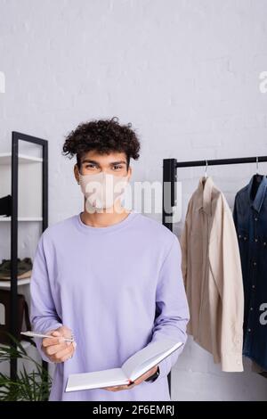 African american showroom proprietor in protective mask pointing at ...