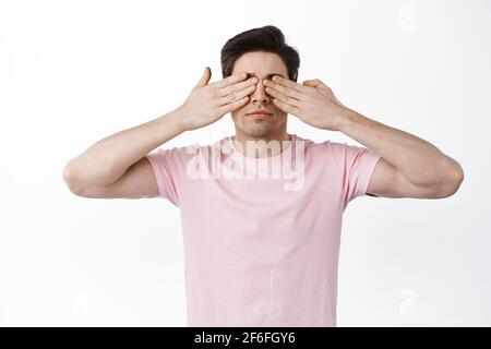 Smiling man cover eyes and waiting for surprise, standing in t-shirt ...
