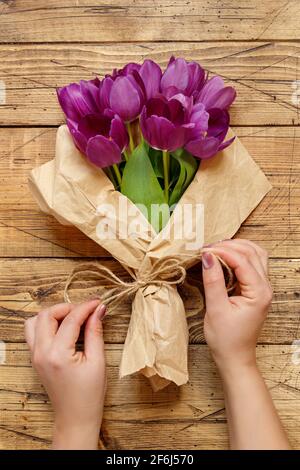 A bouquet of tulips in the hands of a purple background, the boy gives ...