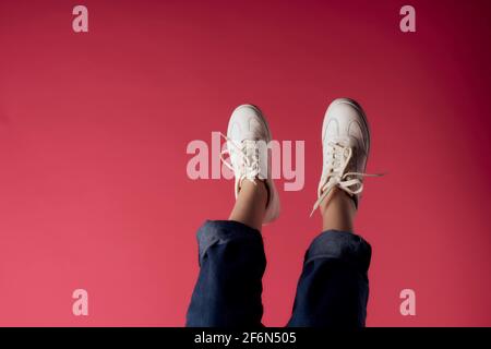 Inverted female legs white sneakers motion street style pink background ...