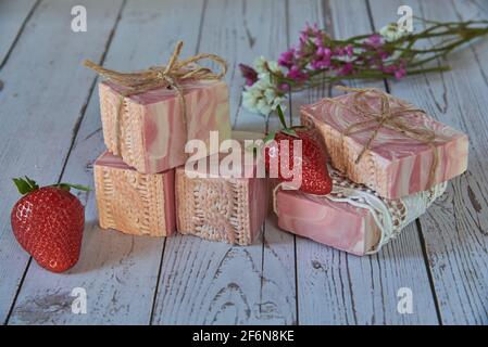 Pink textured handmade soap, lace and strawberries on a wooden ...