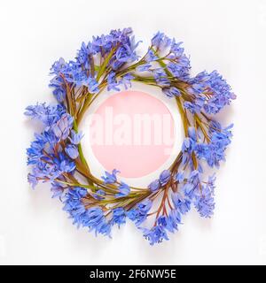 Round frame wreath made of spring flowers on pink background. Top view ...