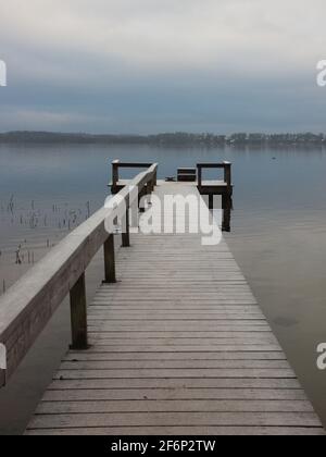 Empty Bathing Pier with wooden railing in winter with Snow and Icy Lake ...