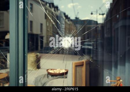 Cracked shop window with reflections of business premises showing Stock ...