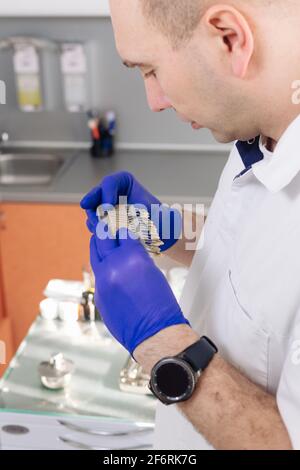 Young man with teeth color chart on yellow background Stock Photo - Alamy