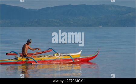 Filipino fisherman prepares to take his outrigger canoe out to fish in ...
