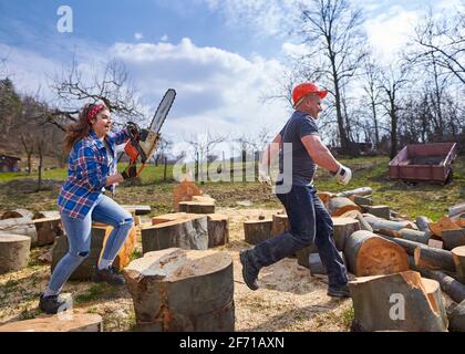 Wife chasing her husband with chainsaw, fooling around Stock Photo - Alamy