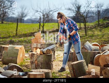 Strong woman lumberjack cutting big logs with her chainsaw Stock Photo ...