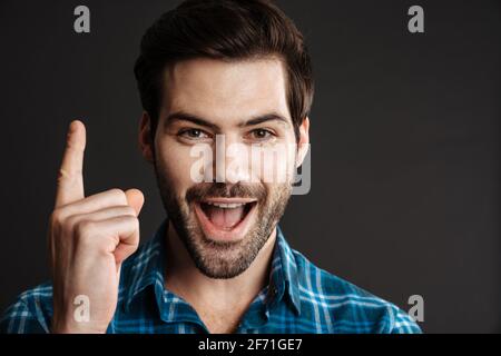 Excited handsome man exclaiming and pointing finger upward isolated ...