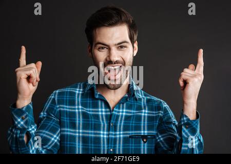Excited handsome man exclaiming and pointing finger upward isolated ...