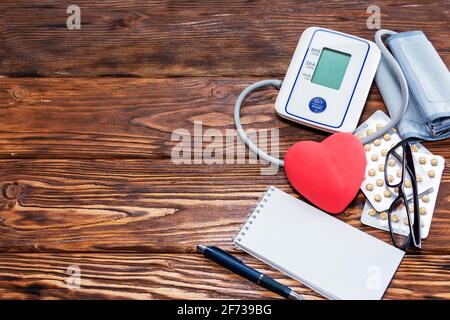 White electric tonometer, red heart and pills, on wooden table Stock ...