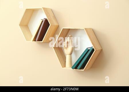 Shelves with books and wooden hand hanging on color wall Stock Photo ...