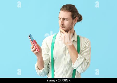 Thoughtful man with calculator on color background Stock Photo - Alamy