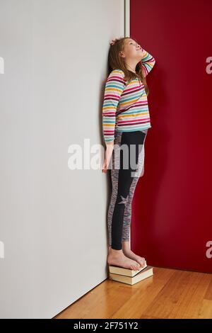 Cute girl measuring height near stadiometer at home Stock Photo - Alamy