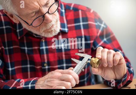 Plumber measuring a plumbing fitting with a caliper; panoramic banner ...