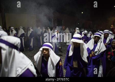Cucuruchos in purple robes process solemnly through the streets of ...