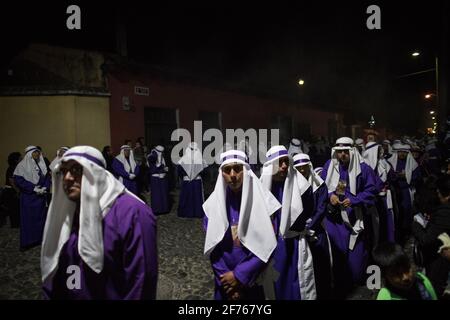 Cucuruchos in purple robes process solemnly through the streets of ...