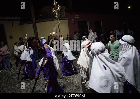 Cucuruchos in purple robes process solemnly through the streets of ...