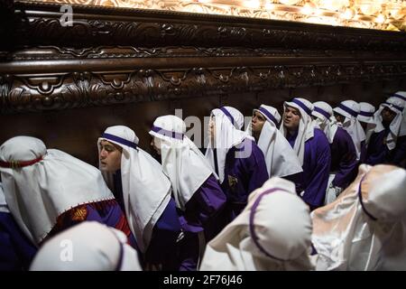 Cucuruchos in purple robes process solemnly through the streets of ...