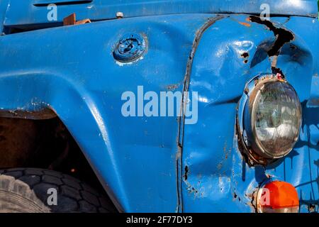 Fragment of an old blue car with a dirty rusted wheel and a scratched ...