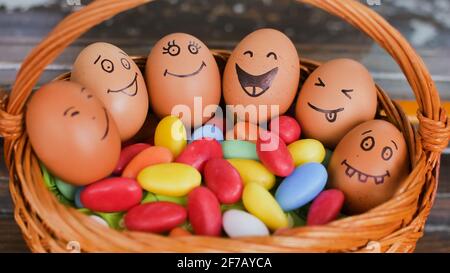 Stack of eggs with hand drawn faces on straw basket, easter preparation ...