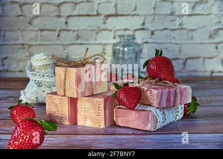 Pink textured handmade soap, lace and strawberries on a wooden ...