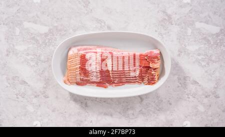 Flat lay. Step by step. Uncooked bacon strips on a baking sheet with ...
