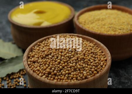 brown Mustard seeds and yellow mustard powder in white bowls on a ...