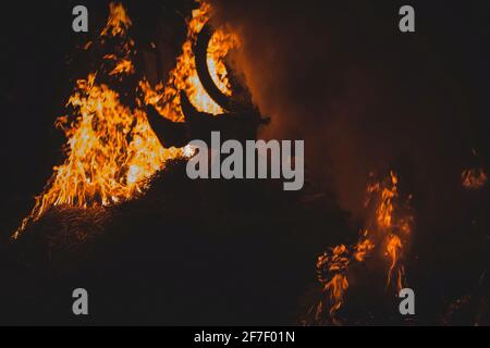 Totally crazy cyclist on a mountain bike riding through bonfire, sparks ...