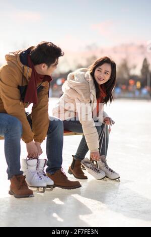 Young loving couple skating at ice rink at night. Man and woman kiss ...