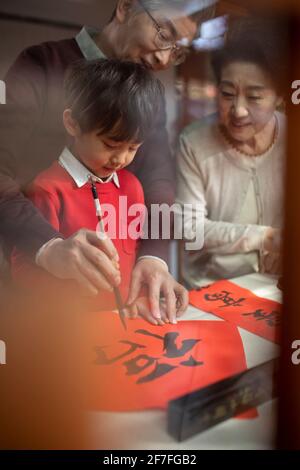 Happy family writing calligraphy on couplets Stock Photo - Alamy