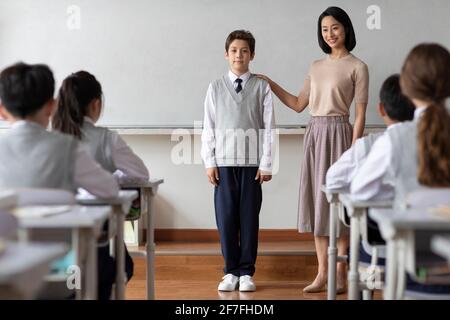 Teacher introducing a new young student to the class Stock Photo - Alamy
