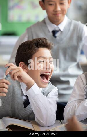 Asian teenage classmates sitting at desk and doing homework together ...