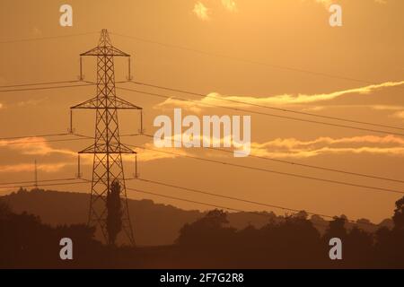 Electricity Pilon against a sunset sky and could Stock Photo - Alamy
