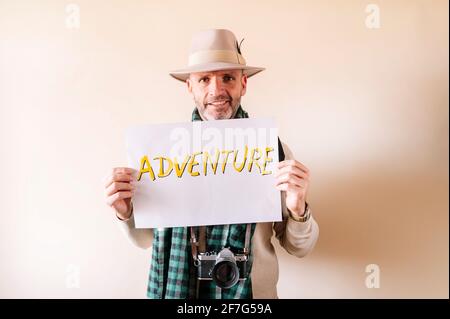 Man holding ADVENTURE sign with hat and backpack Stock Photo - Alamy