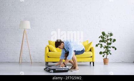 man in blue shirt packing baggage in modern living room Stock Photo - Alamy