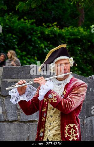 A musician dressed in 18th century style clothing plays a fife at a ...